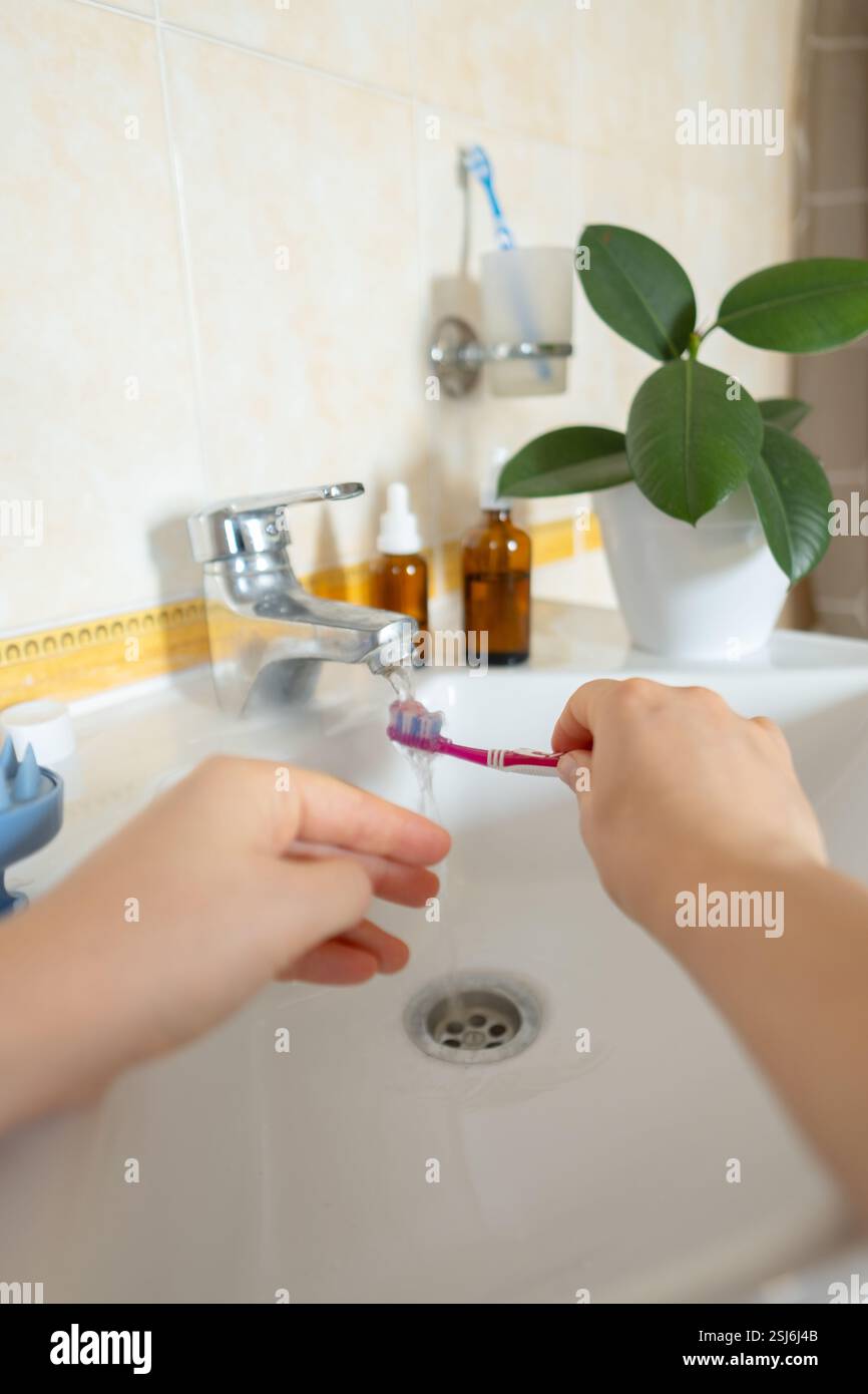 Woman brushes her teeth and carefully washes the toothbrush after use ...