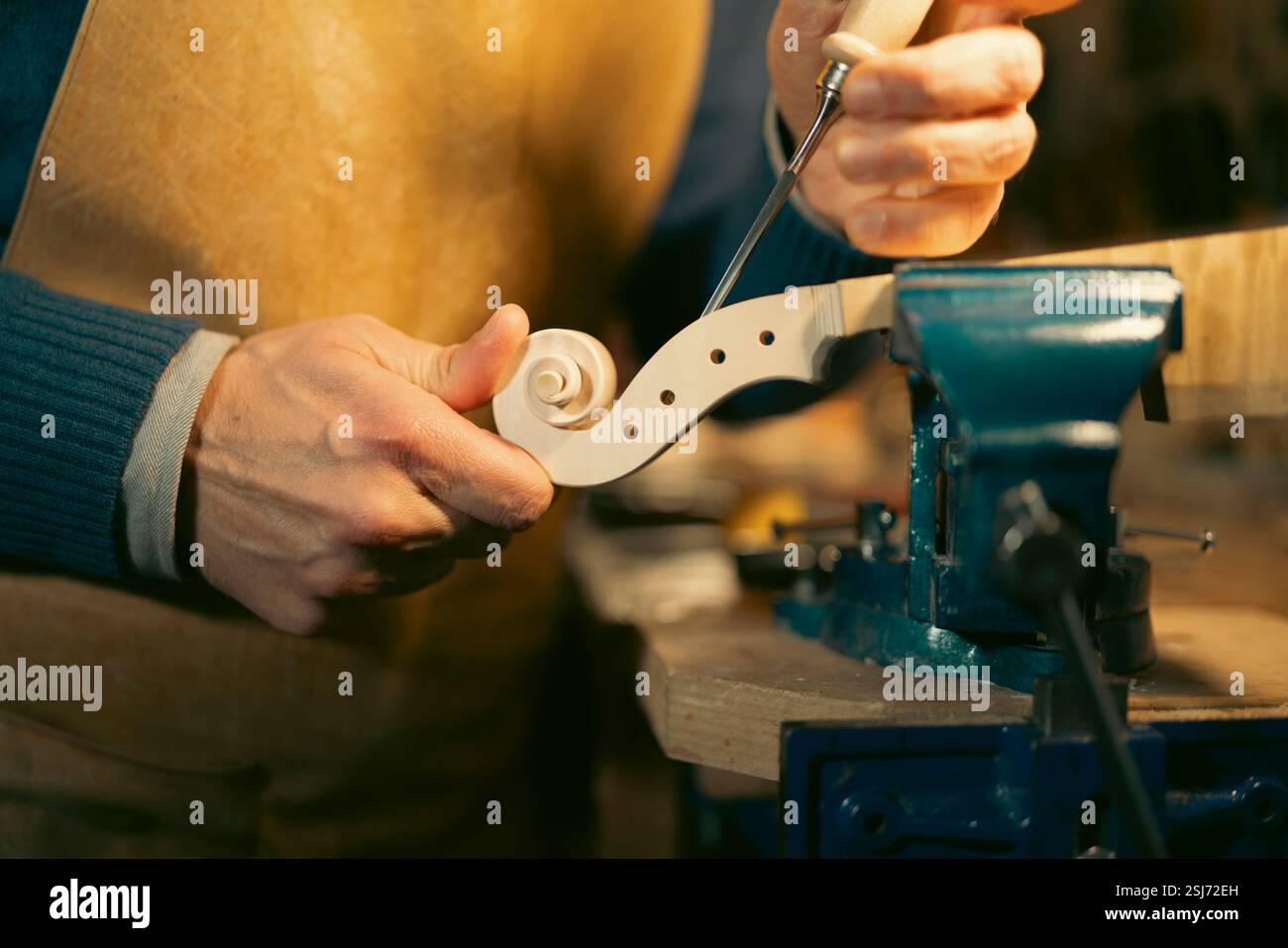 Skilled luthier meticulously working on a violin scroll in his workshop ...
