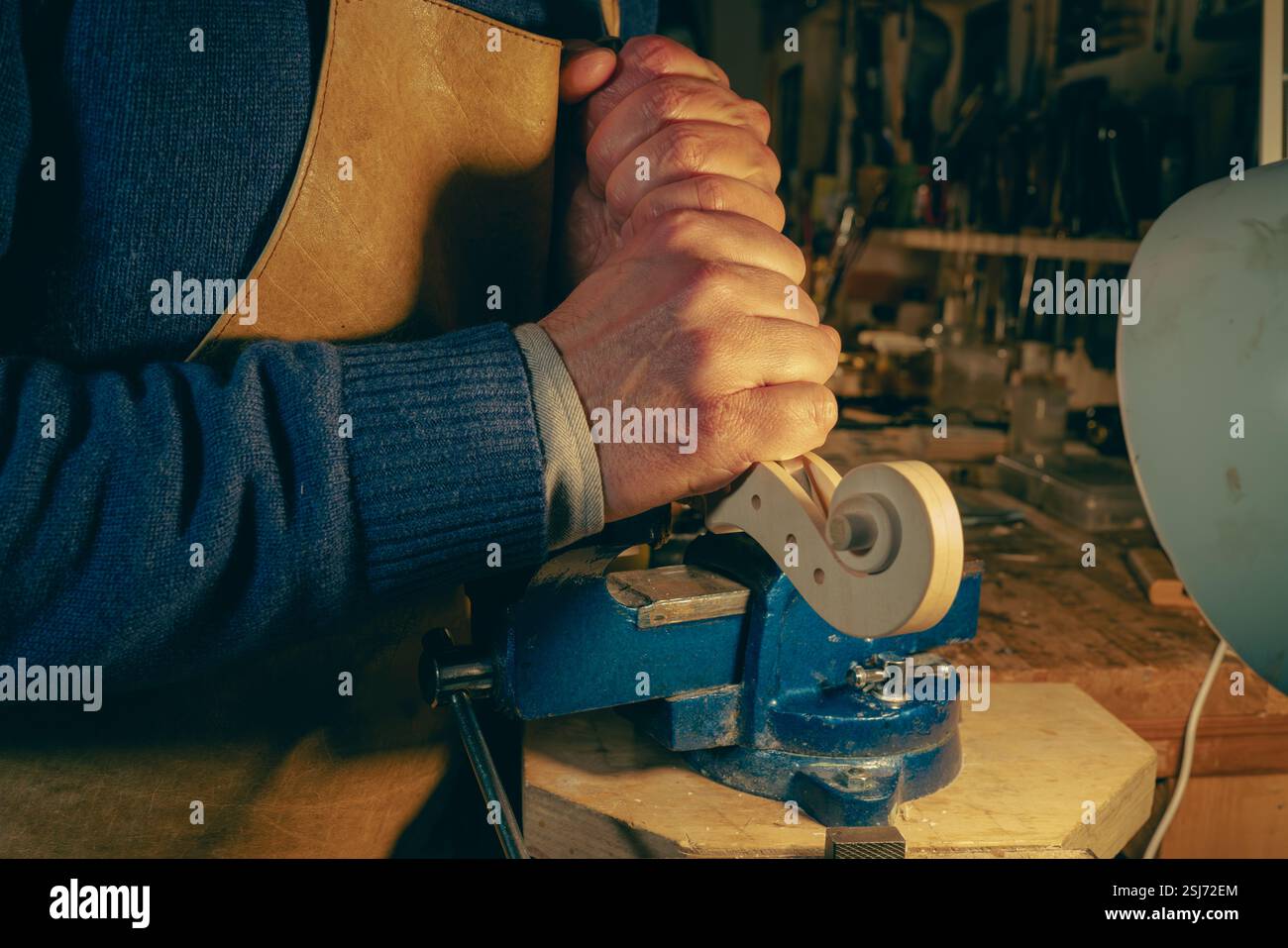Italian luthier is carefully crafting a violin scroll in his workshop ...