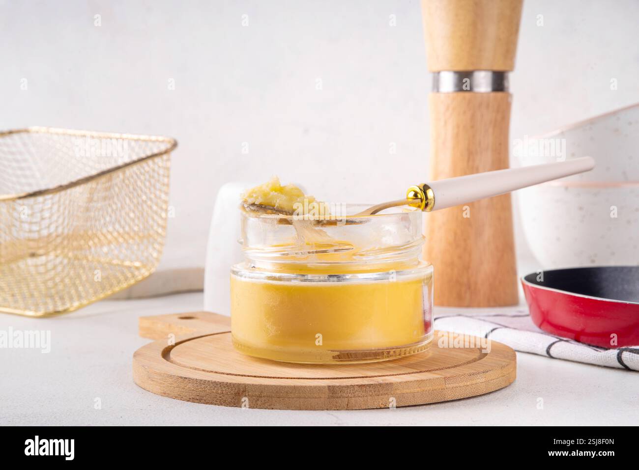 Homemade ghee butter in small glass jar on white kitchen table ...