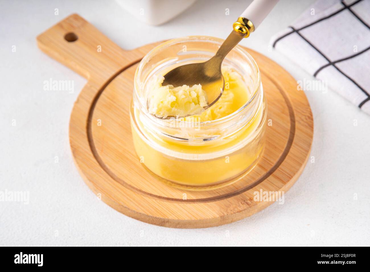 Homemade ghee butter in small glass jar on white kitchen table ...