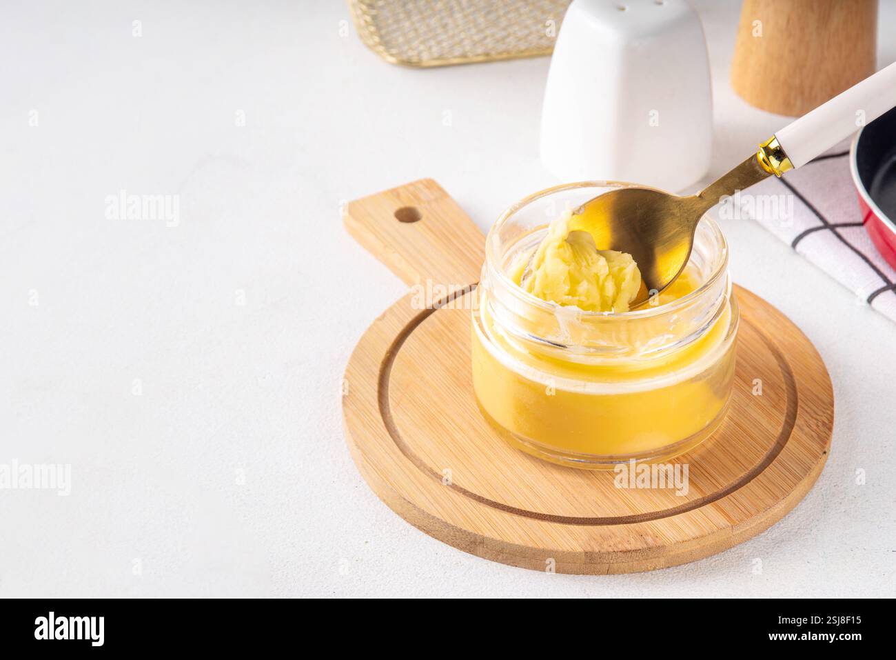 Homemade ghee butter in small glass jar on white kitchen table ...