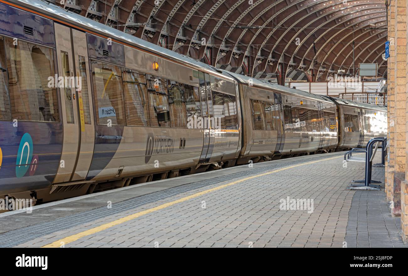 A train is stationary at a railway station platform and the carriages ...