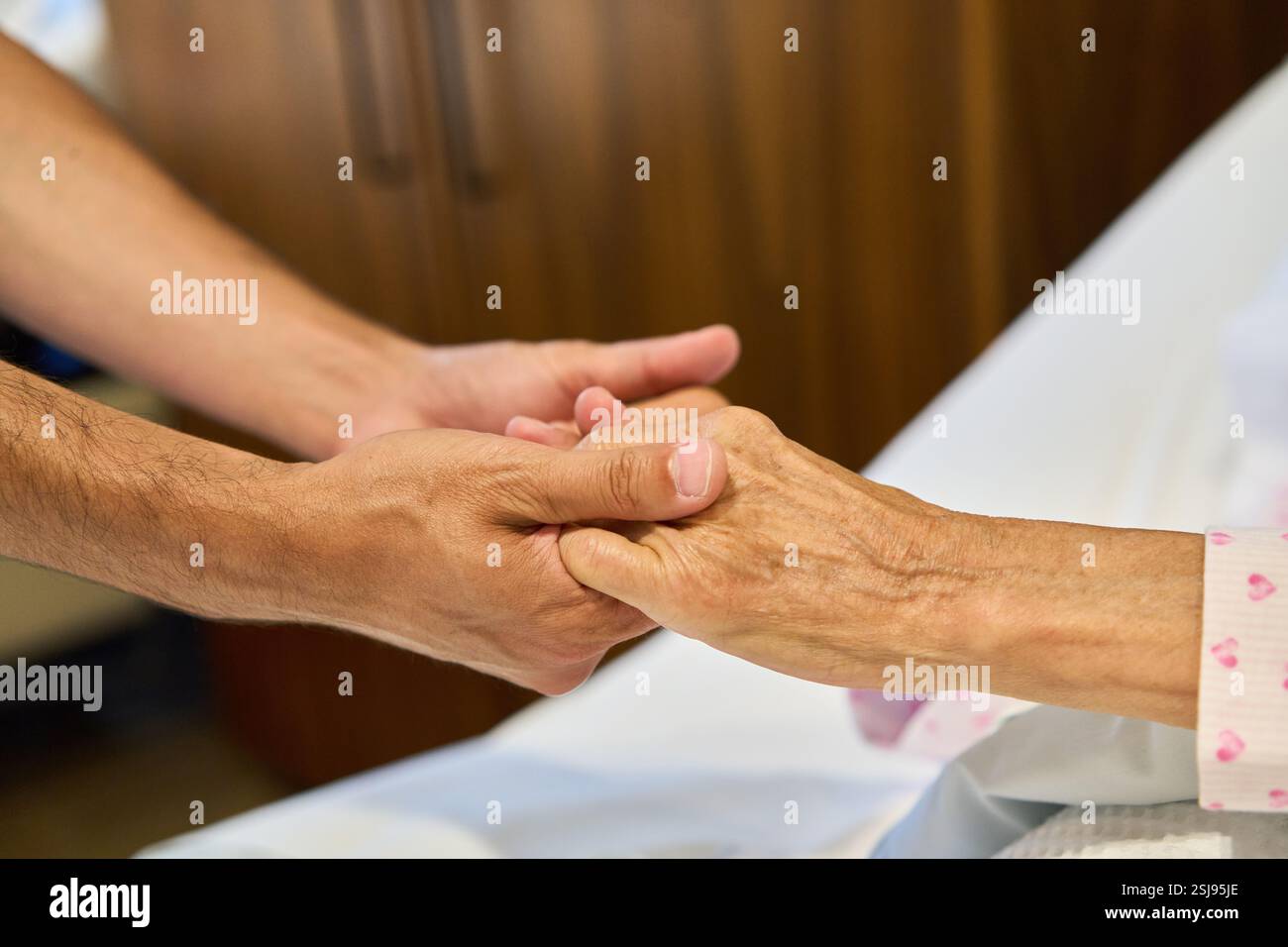 Close-up of a caregiver gently holding hands with a senior patient ...