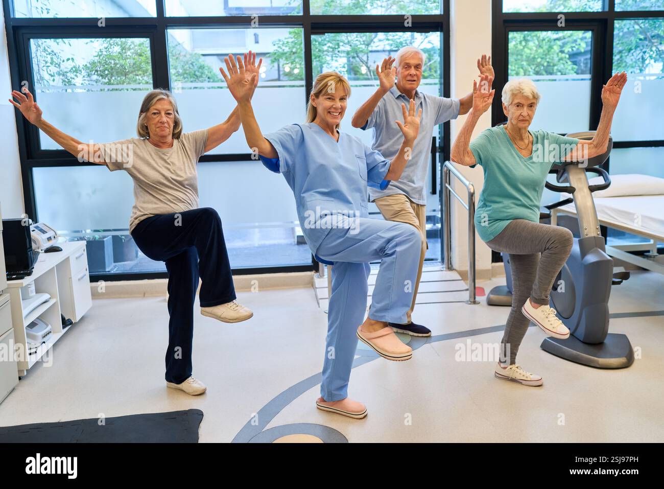Seniors engaged in a group exercise class with a trainer in a ...