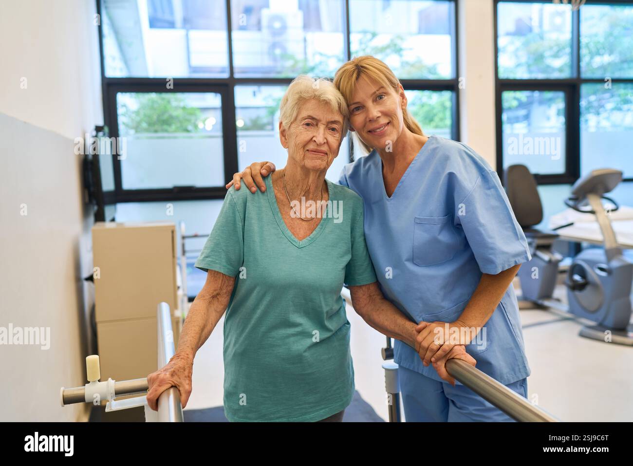 A senior woman receiving assistance from a nurse while exercising. The ...