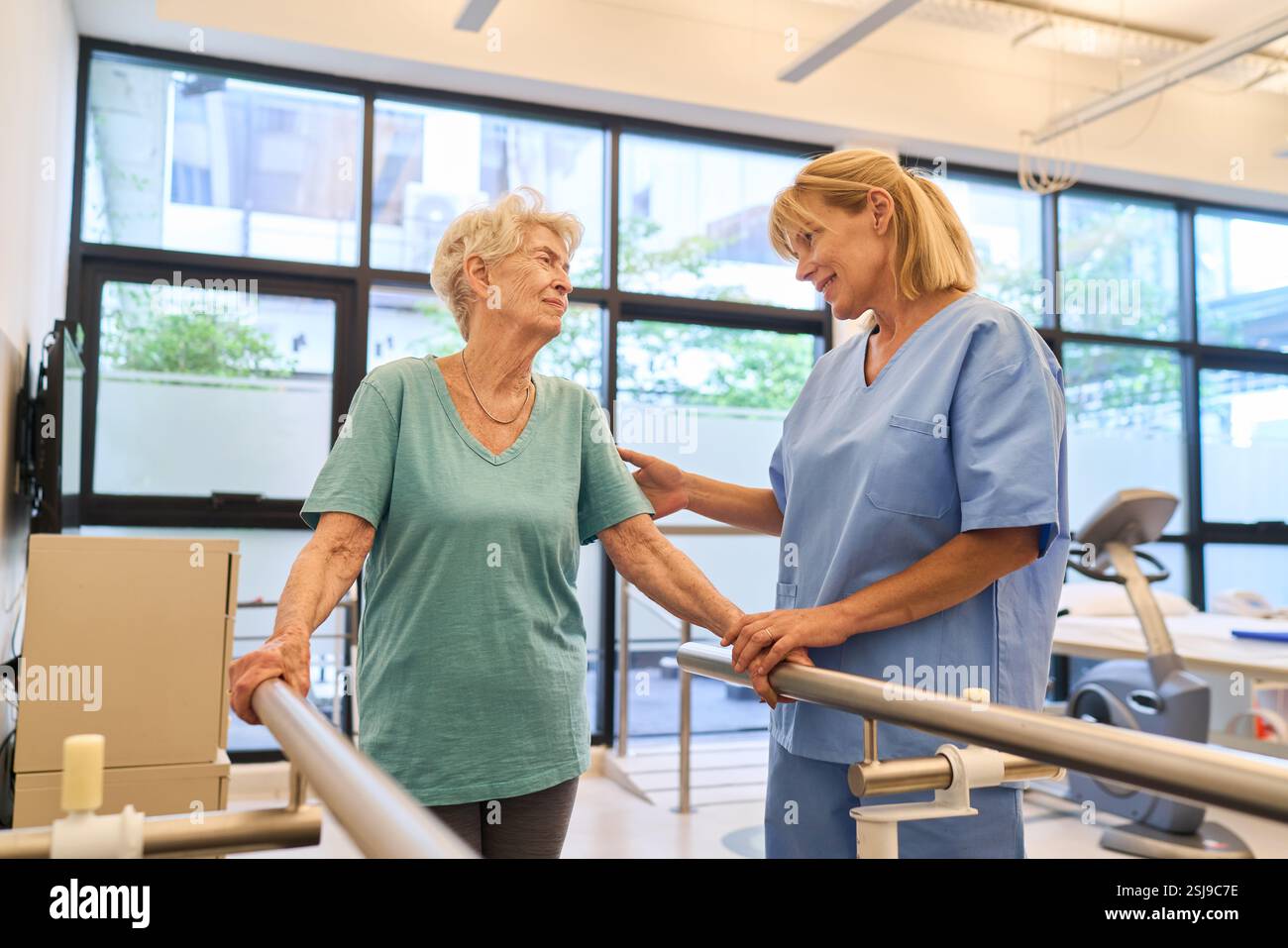 A nurse helps an elderly woman with physical therapy exercises in a ...