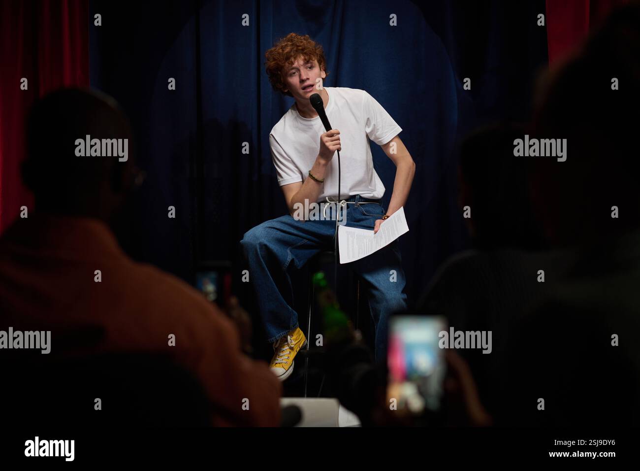 Person performing stand-up comedy on stage holding microphone and ...