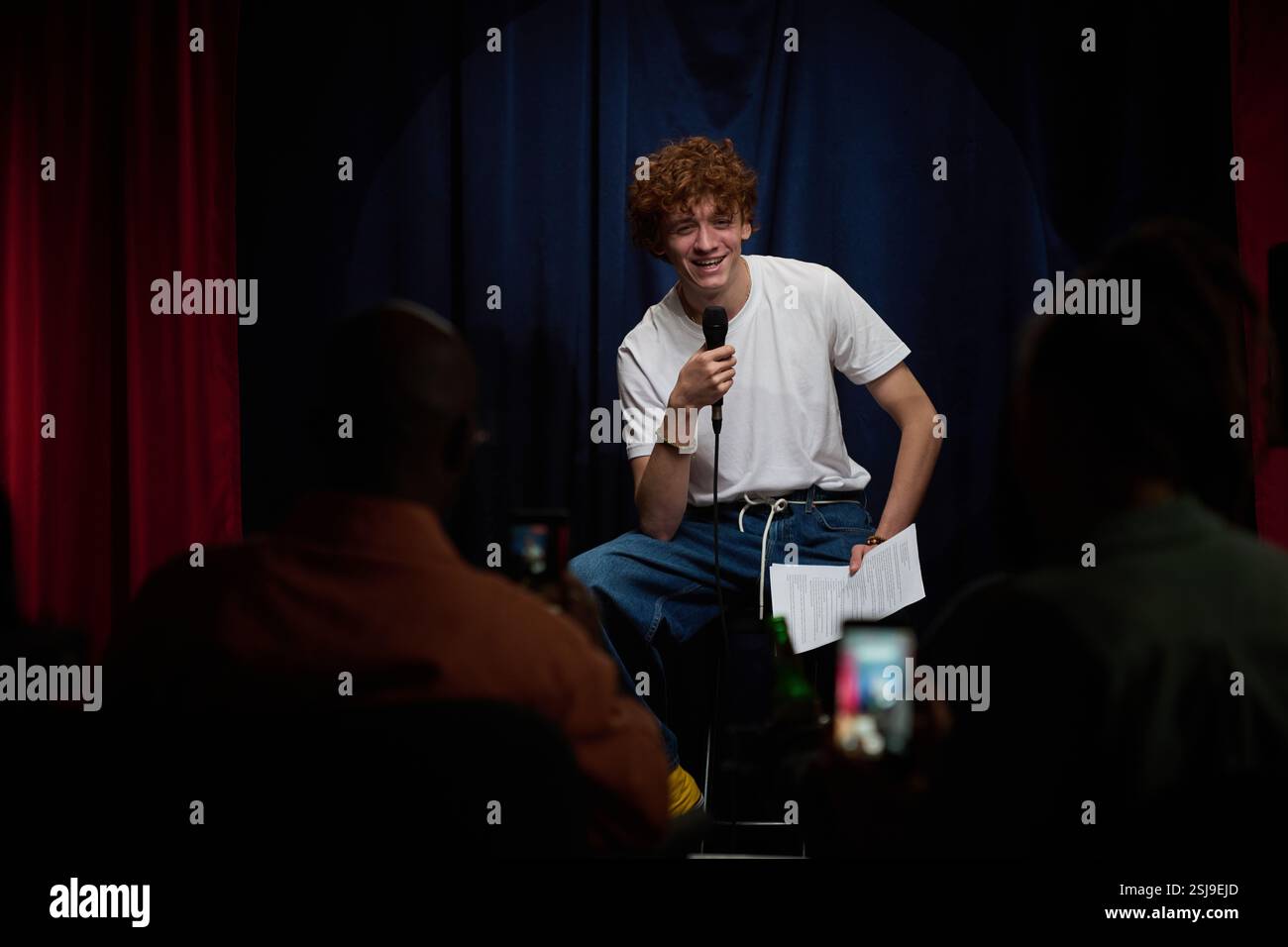 Comedian in white shirt joyfully delivering a stand-up performance on ...