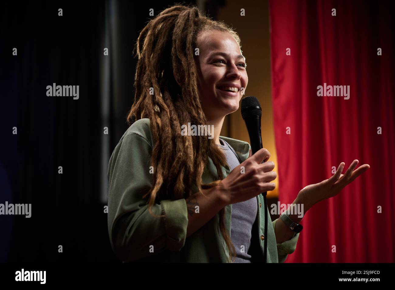 Woman with dreadlocks smiling while giving presentation on stage ...
