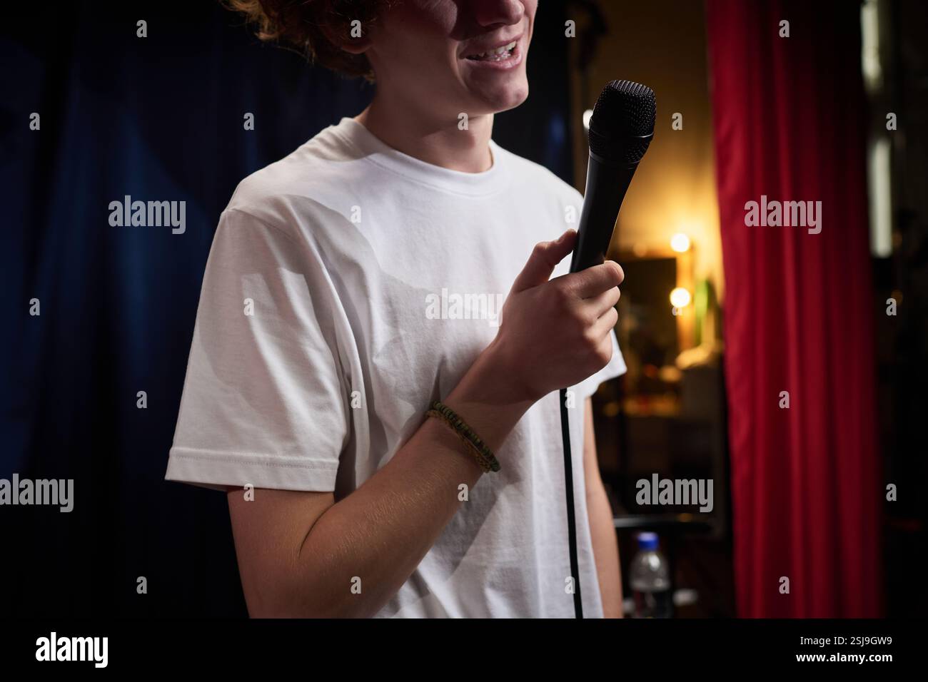 Person holding microphone on stage, performing in front of an audience ...