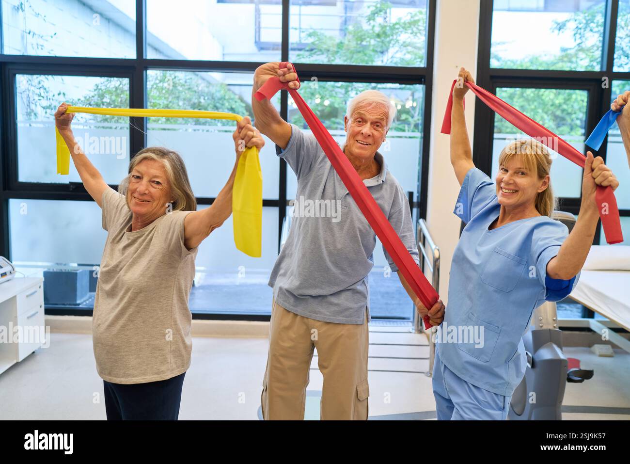 A group of seniors performs therapy exercises using resistance bands ...