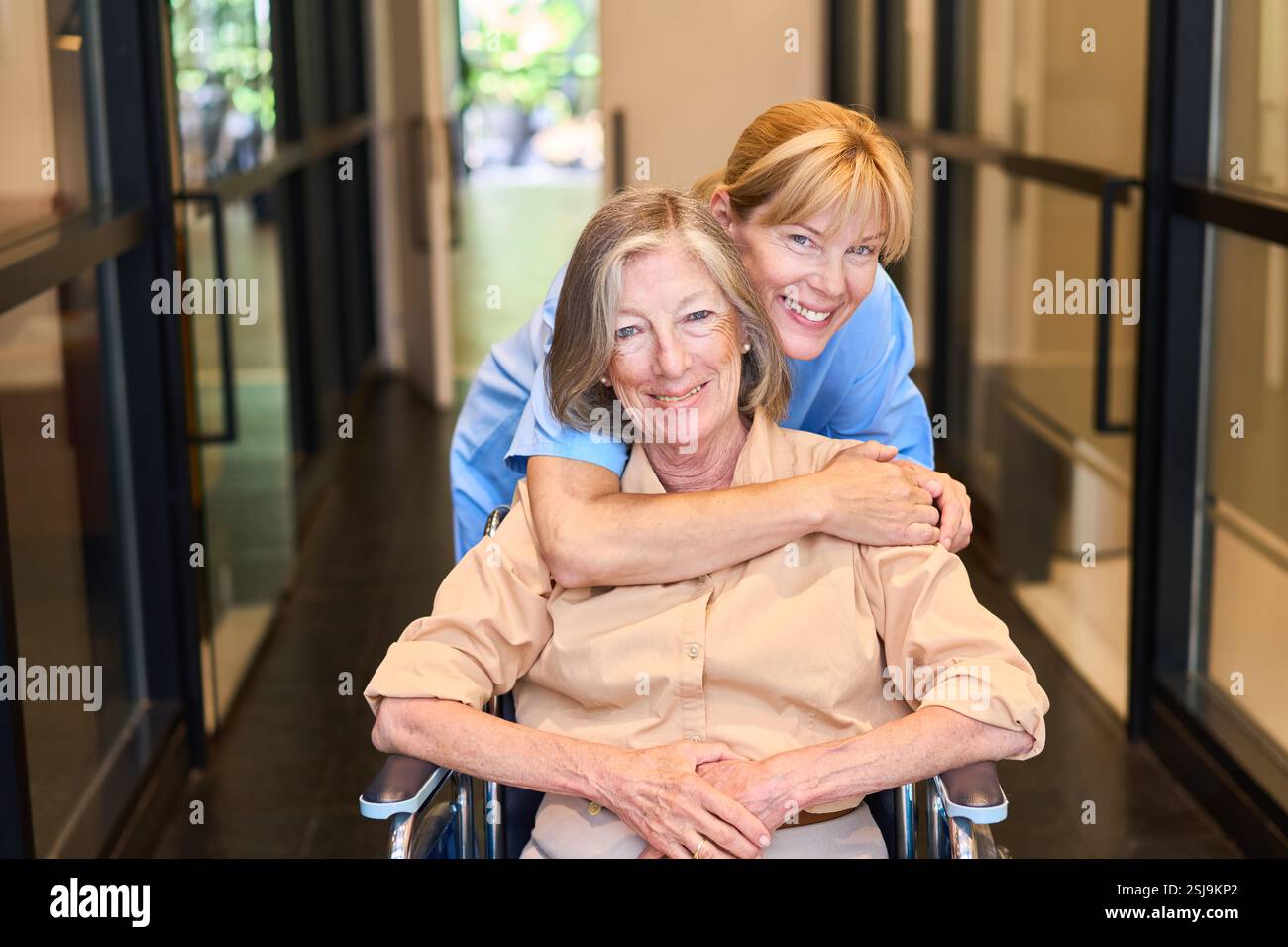 A compassionate caregiver hugs an elderly woman in a wheelchair ...
