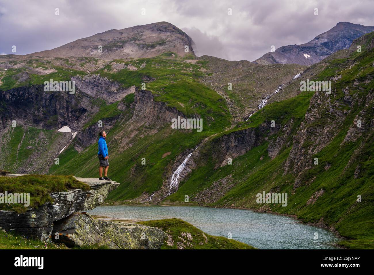 Lone traveler stands on rock and admires majestic mountain view on ...