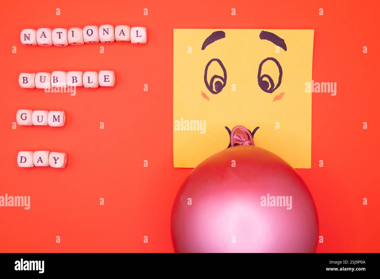 A concept of an emoticon note, blowing a bubble of bubble gum on a red ...