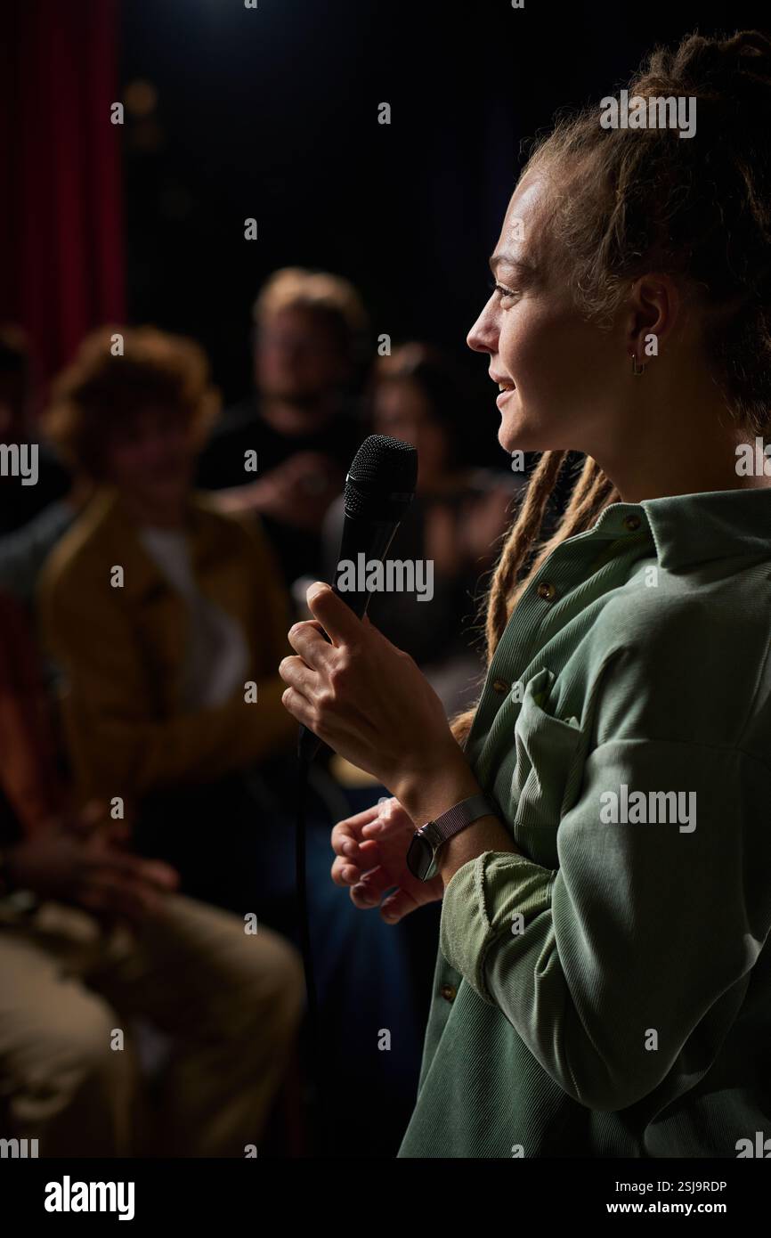 Woman holding a microphone while performing stand-up comedy on stage in ...