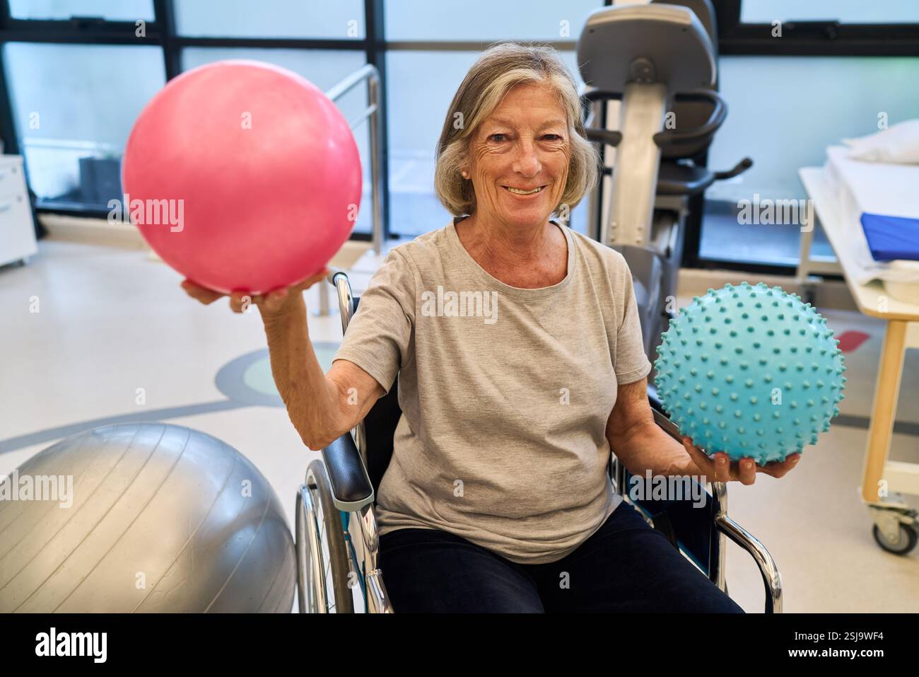 A senior woman sitting in a wheelchair is holding colorful therapy ...