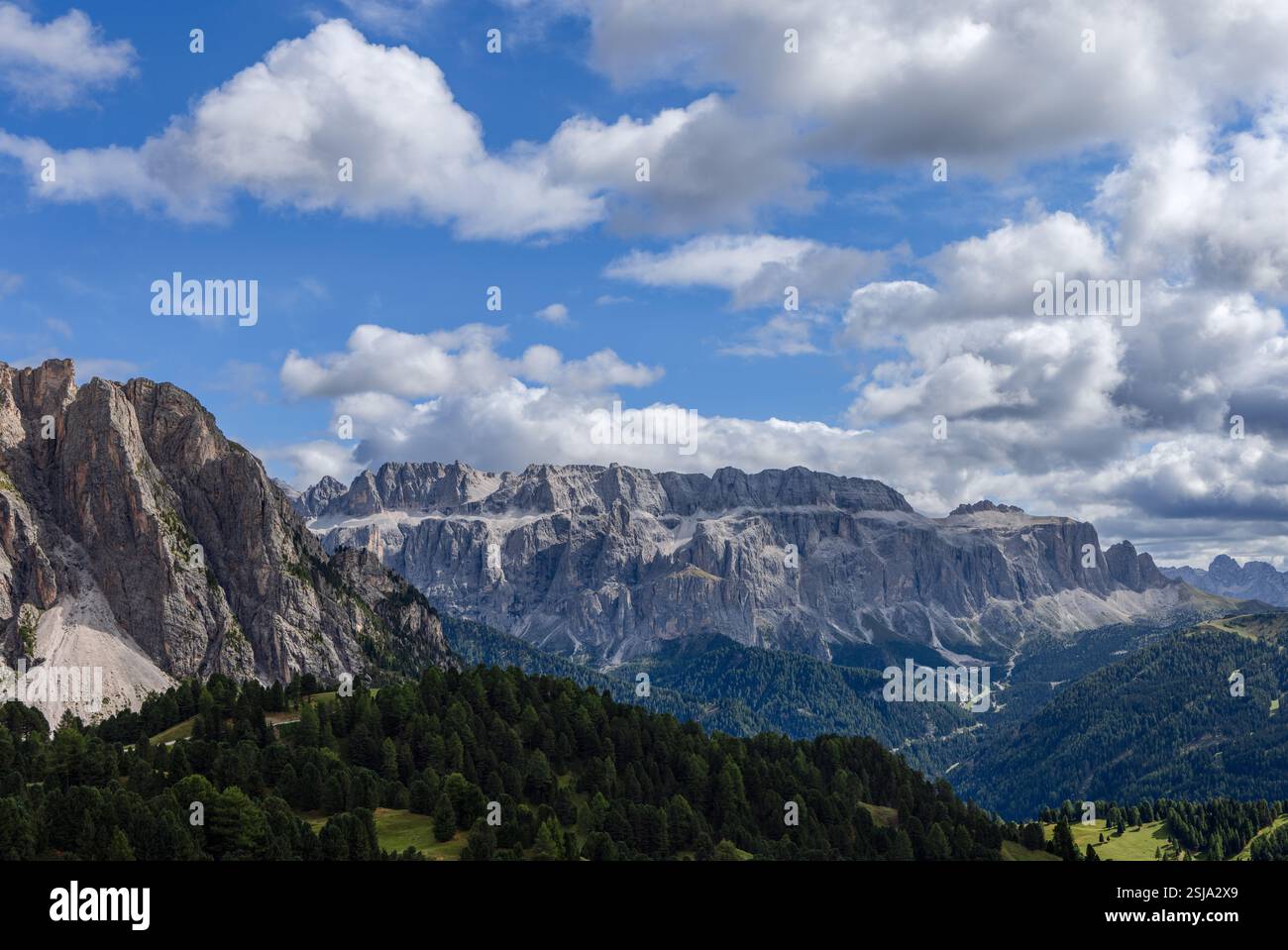 The towering cliffs of the Dolomites in Italy rise above dense green ...