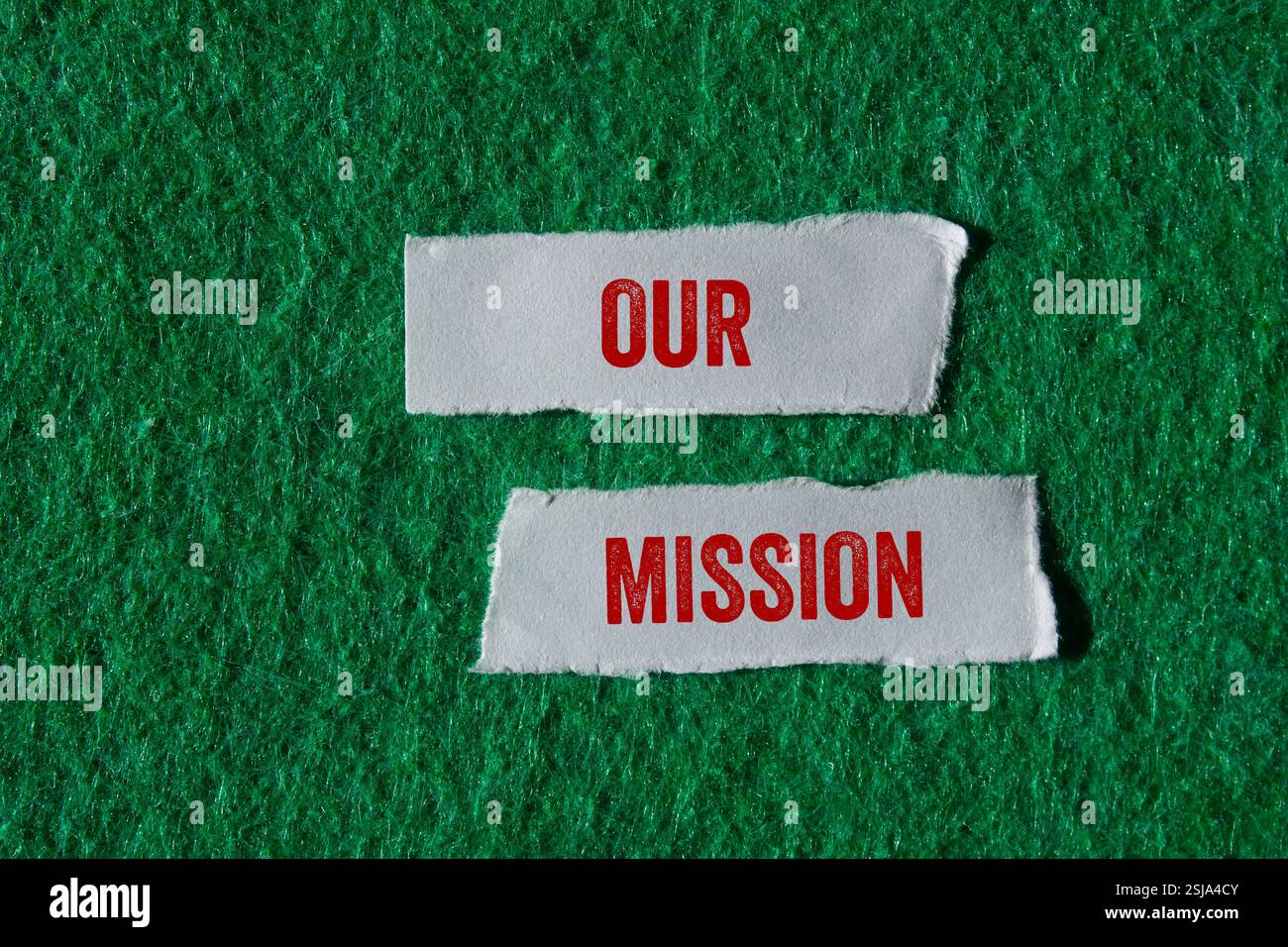 Our mission message written on ripped torn paper pieces on green background. Conceptual our ...