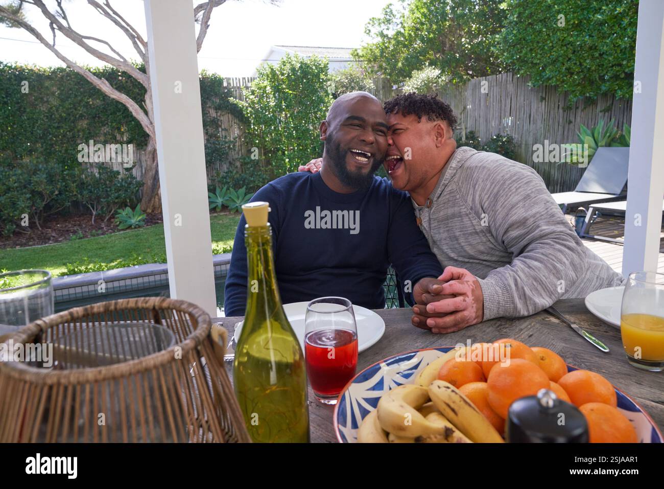 Gay couple laughing at table on patio Stock Photo - Alamy