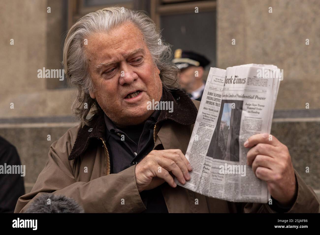 Steve Bannon reads a front page of the New York Times while speaking to ...