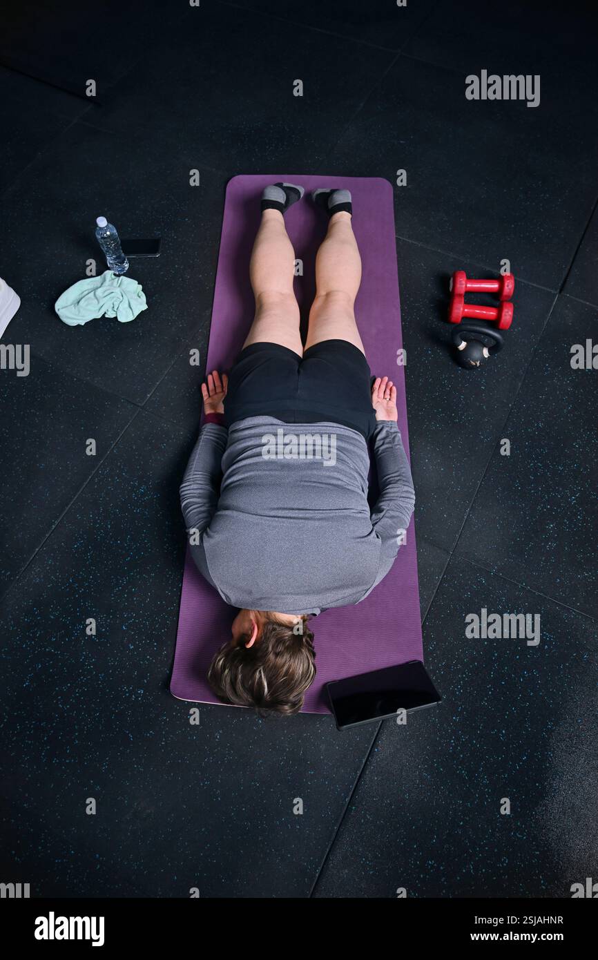 Person lying down on yoga mat in gym Stock Photo - Alamy