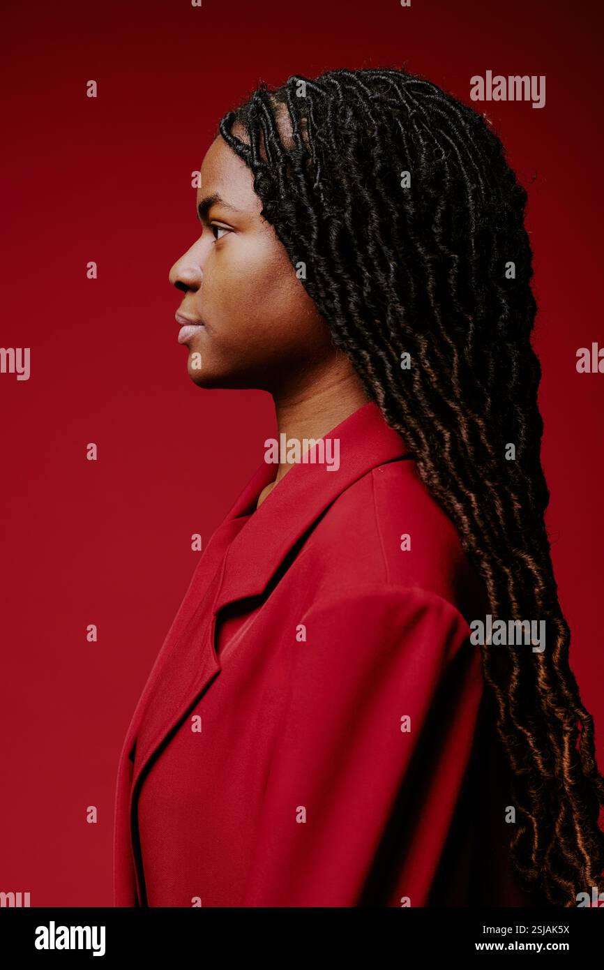Focused on womans side profile with long braided hair and wearing red ...