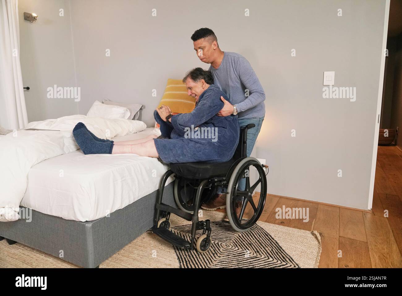 Man helping disabled friend getting out of bed Stock Photo - Alamy