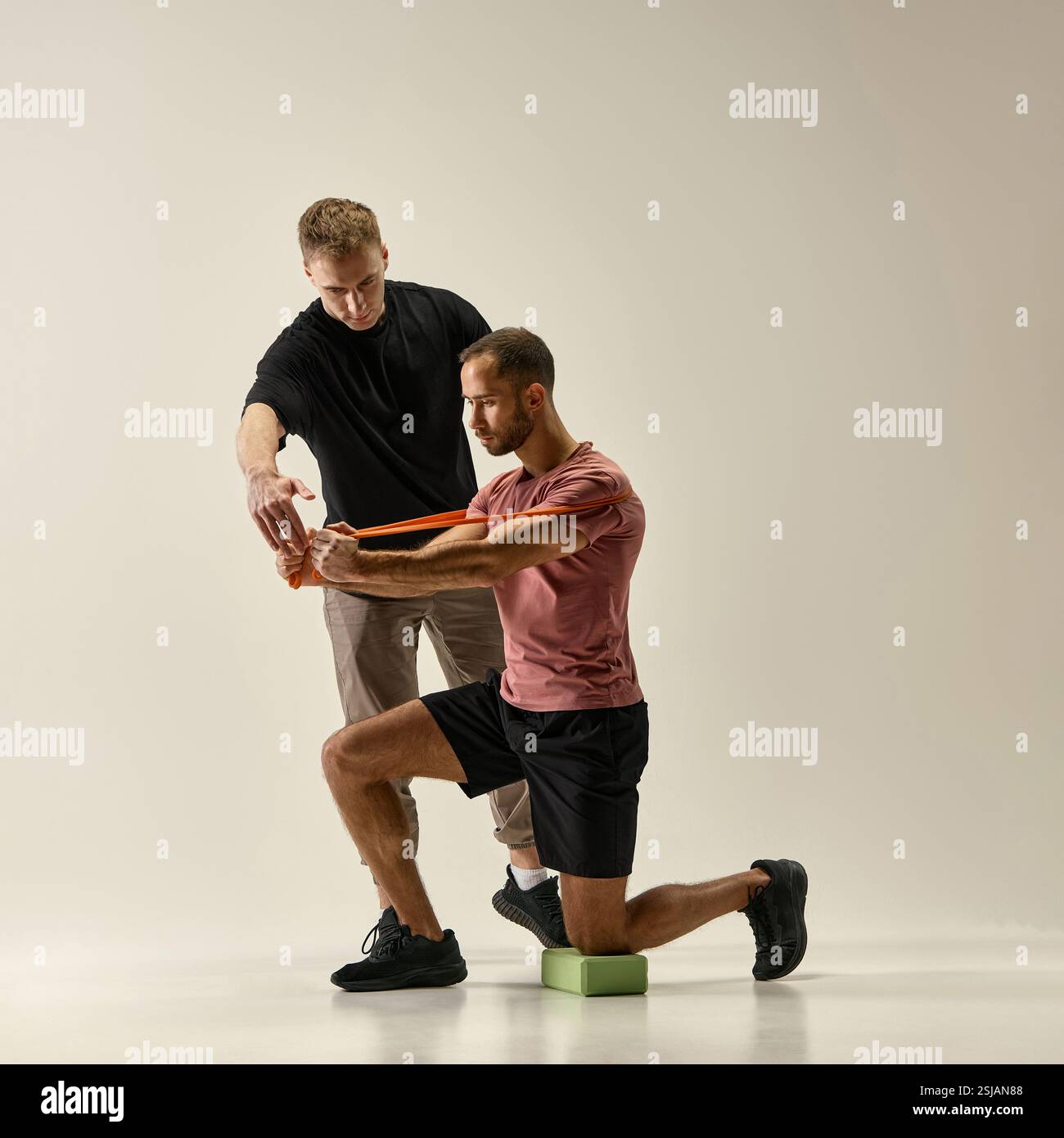 Trainer guiding man in half-kneeling resistance band exercise ...