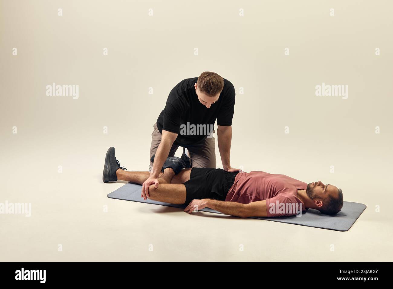 Trainer guiding man through spinal twist stretch, stabilizing leg while ...