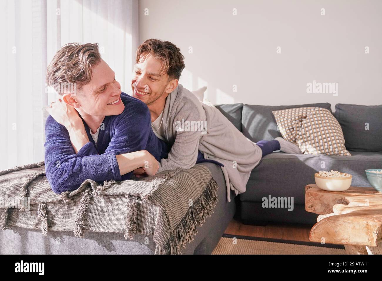 Happy gay couple relaxing on sofa Stock Photo - Alamy