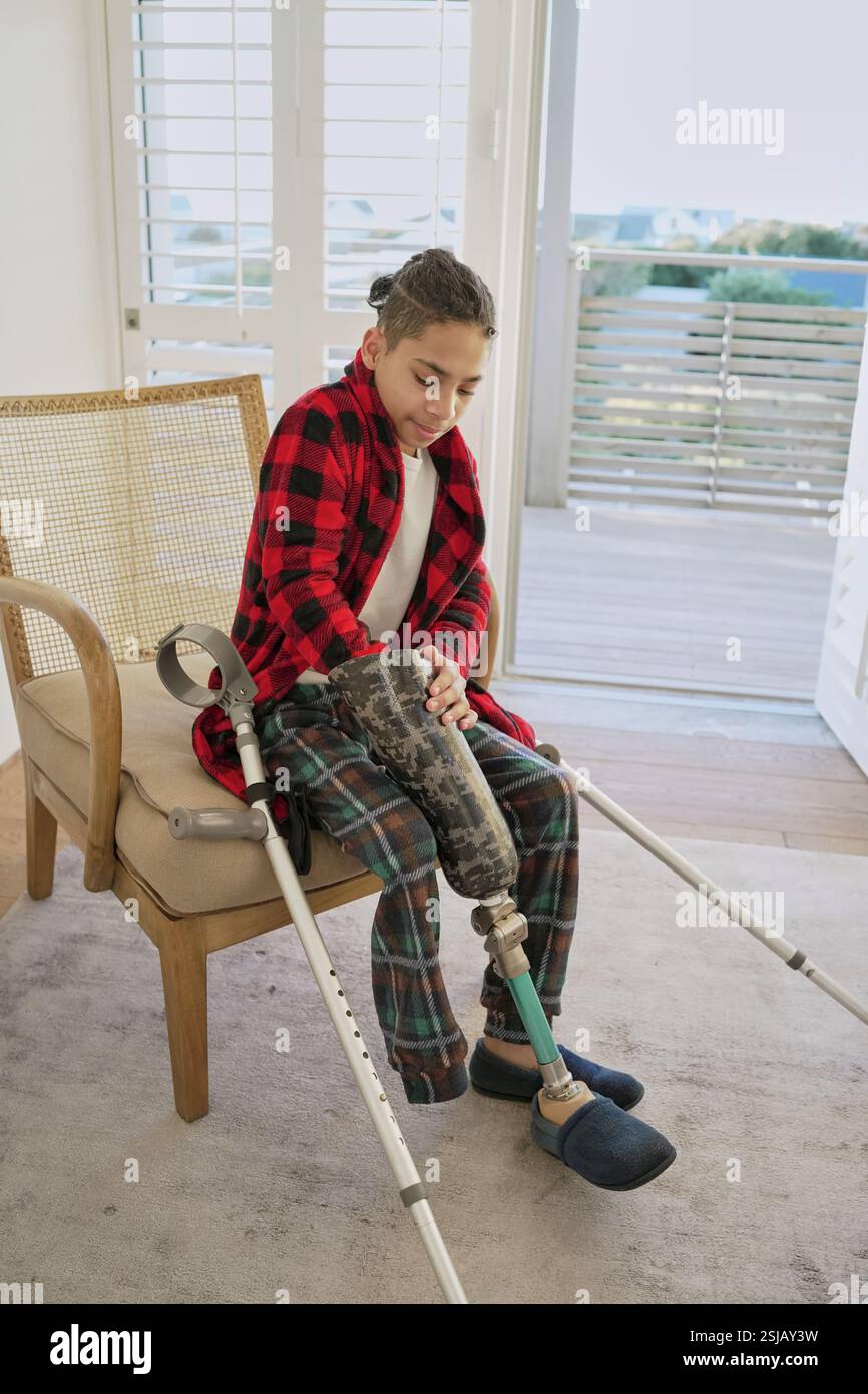 Teenage boy with leg prosthesis sitting on armchair Stock Photo - Alamy