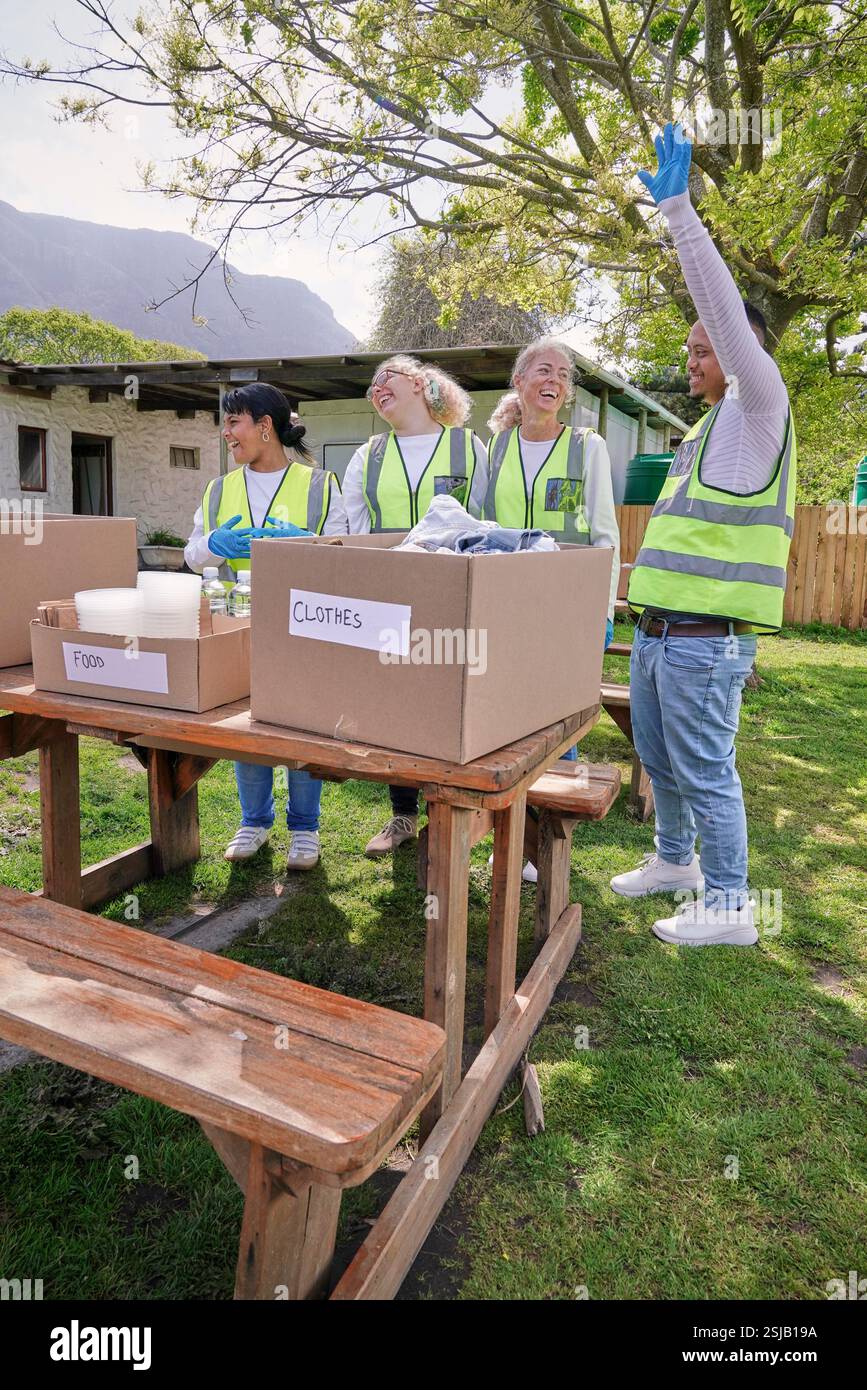 Group of volunteers standing next to donation boxes at table outdoors ...