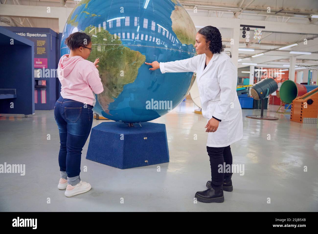 Teenager and instructor looking at globe at science center Stock Photo ...