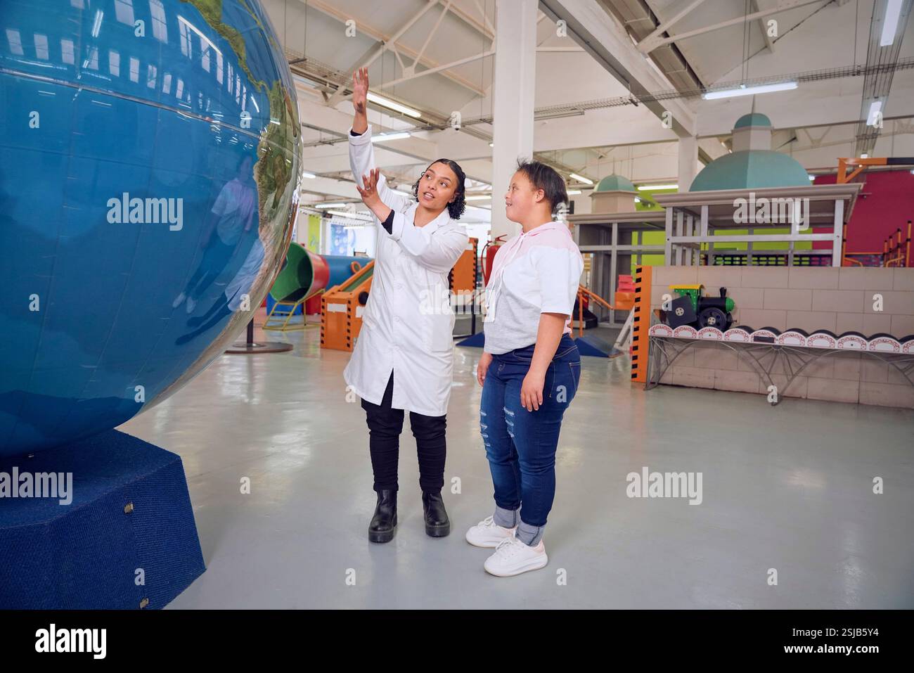 Teenager and instructor looking at globe at science center Stock Photo ...