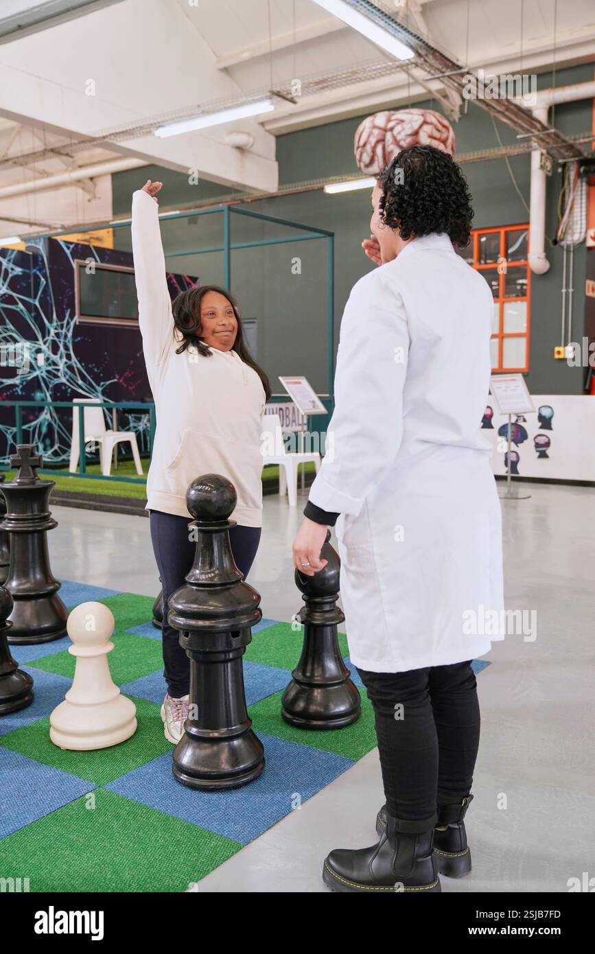 Girl playing with instructor on large scale chess board at science ...