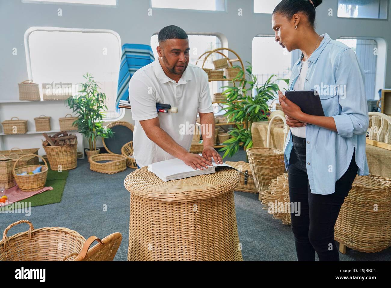 Two employees standing and talking in crafts shop with wicker furniture ...