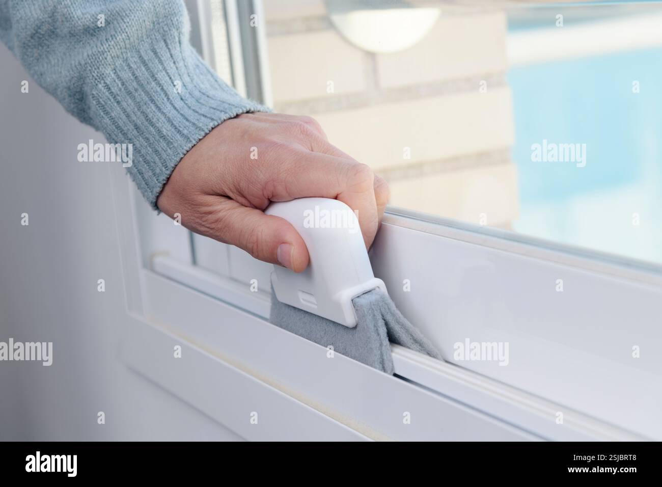 closeup of a man cleaning the track of a white sliding window frame ...