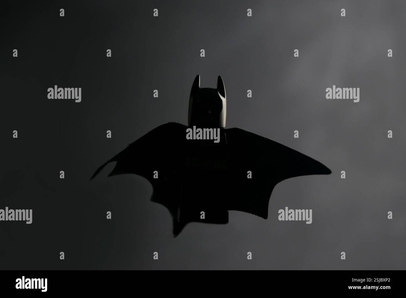 Lego Batman minifigure in dramatic flight pose with cape spread wide, isolated on a white ...