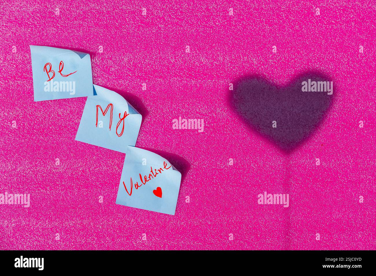 A delicate pink sticky note featuring "Be My Valentine" in handwritten ...