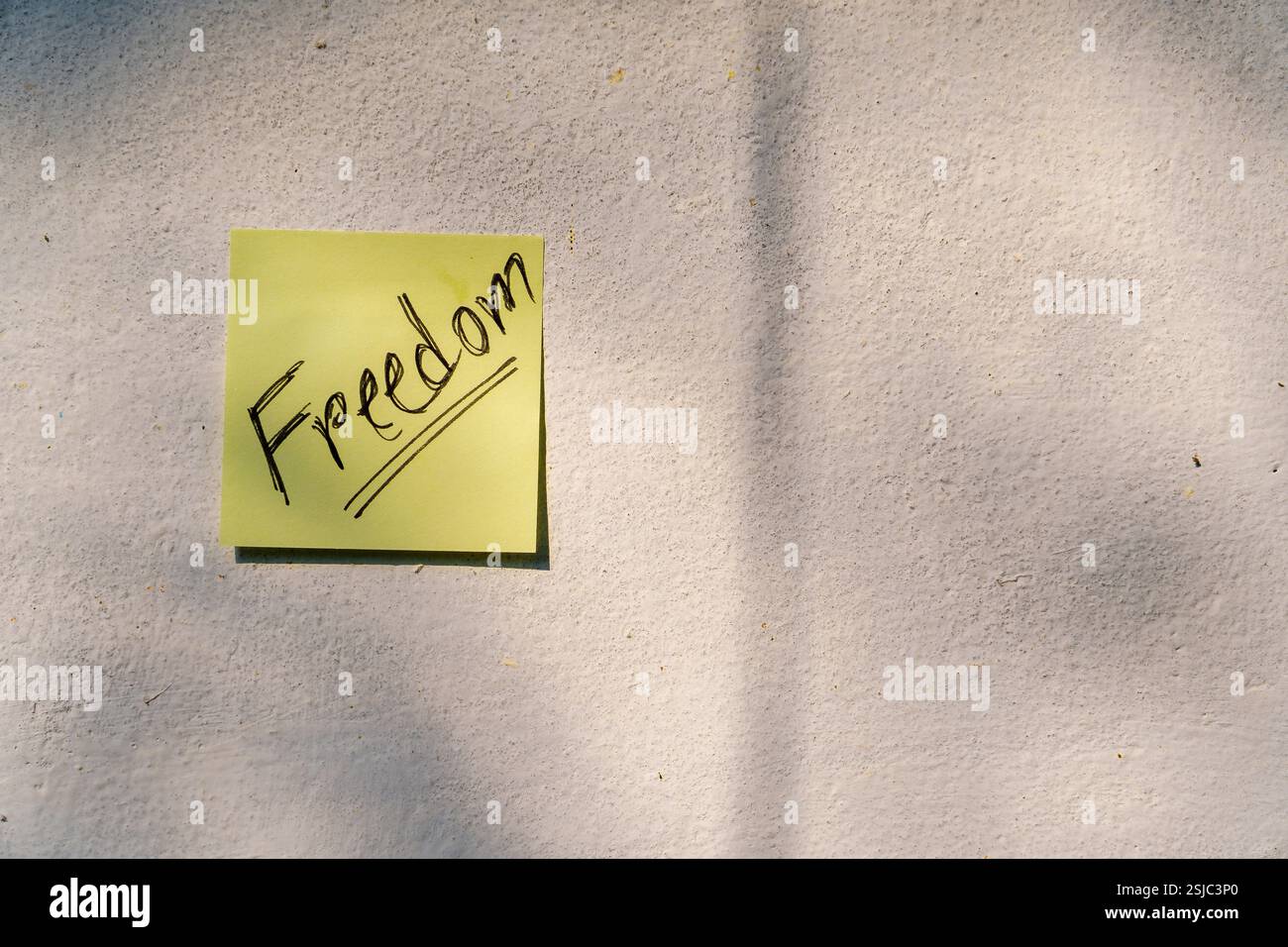 A yellow sticky note with "Freedom" written in bold, placed on a dark ...