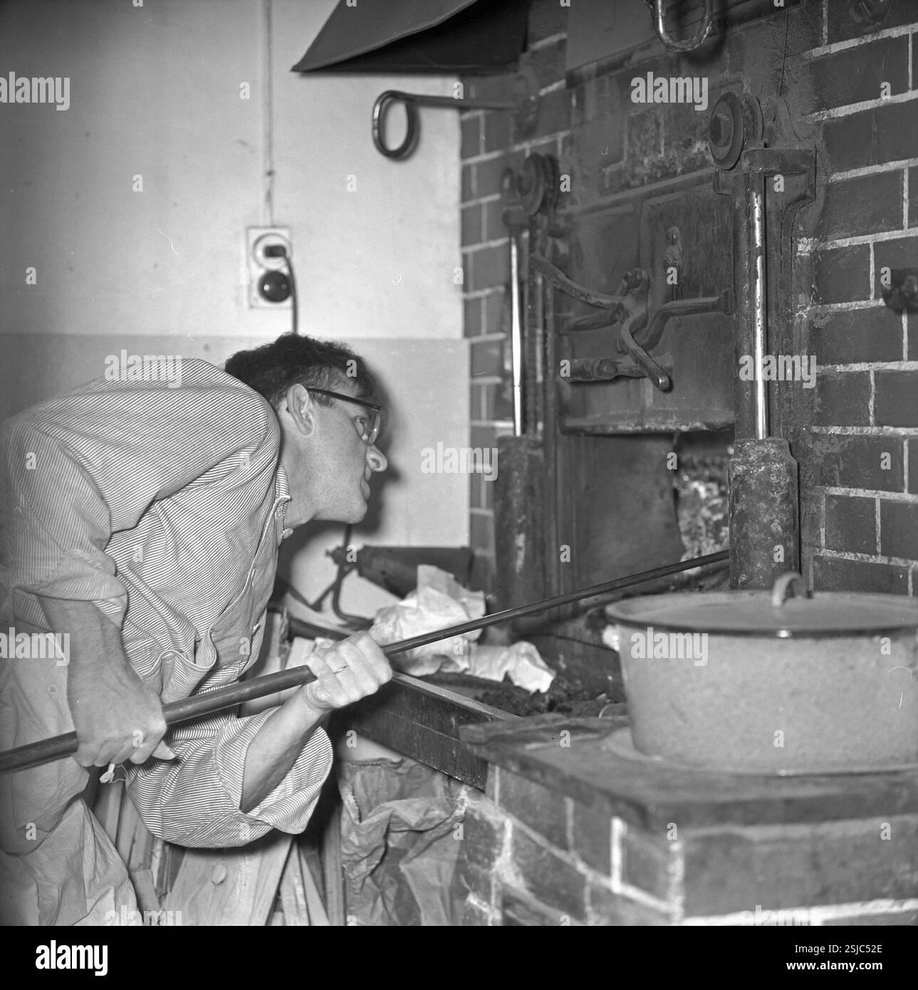 Bäcker entnimmt Brote aus dem Holzbackofen; 1965#Baker removing bread ...