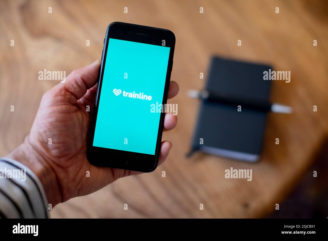 A mobile phone being held showing the Trainline app open on screen ...