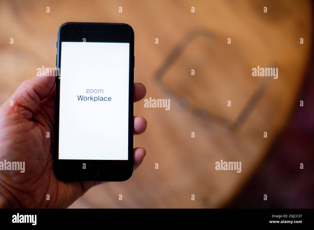 A mobile phone being held showing the Zoom Workplace app open on screen ...