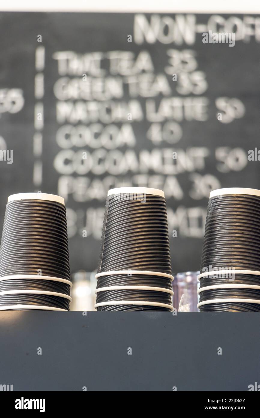 Disposable cups on a coffee shop counter with a daily menu in the ...