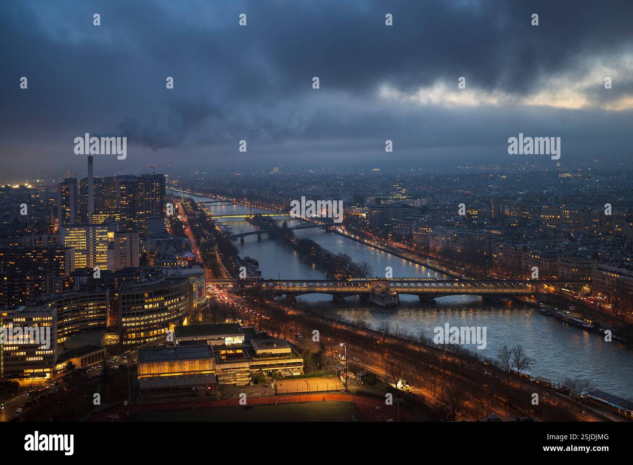 Paris cityscape at dusk, with tall chimney venting steam into grey sky ...