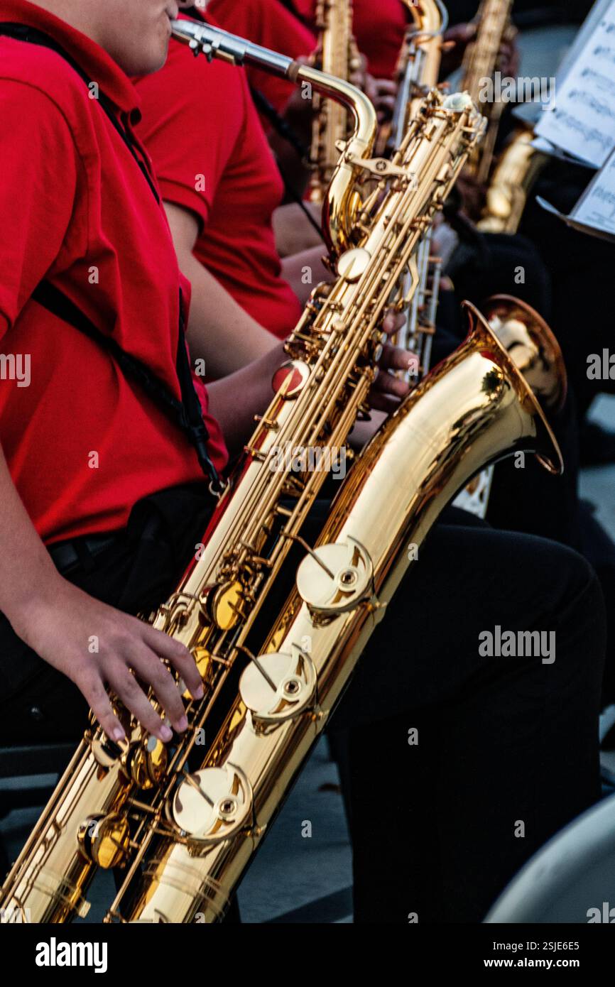 A musician plays the baritone saxophone in a band. The saxophone ...