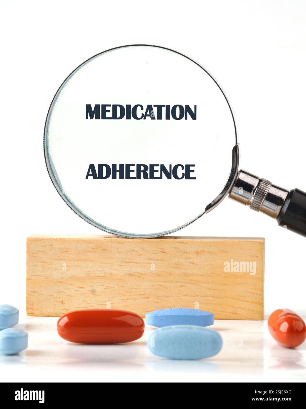 A magnifying glass over a wooden block and colorful tablets highlights ...