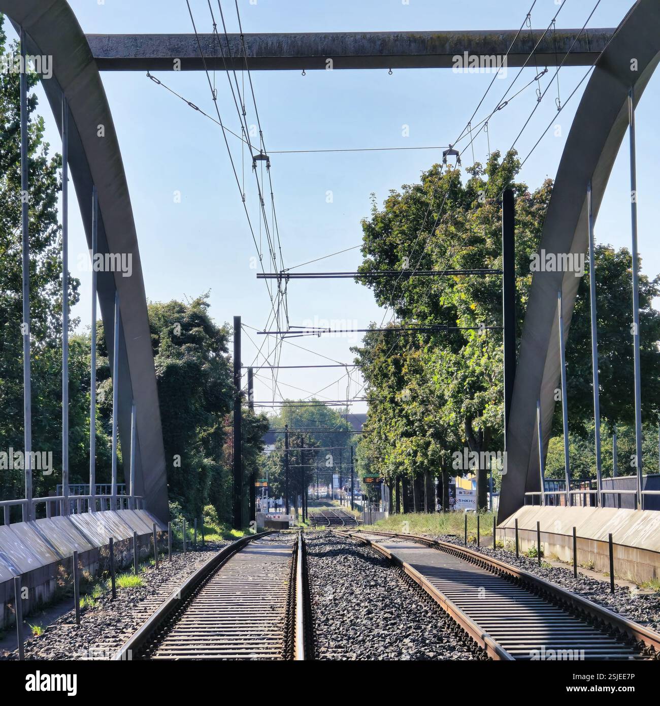 A captivating view of train tracks leading gracefully under a bridge ...
