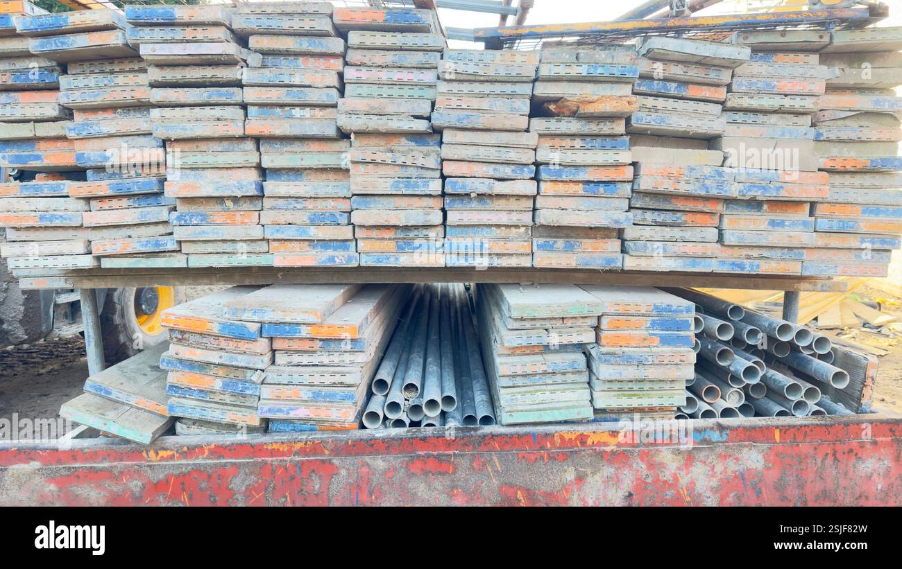 Stacked scaffolding planks and metal pipes on a rusty red platform ...